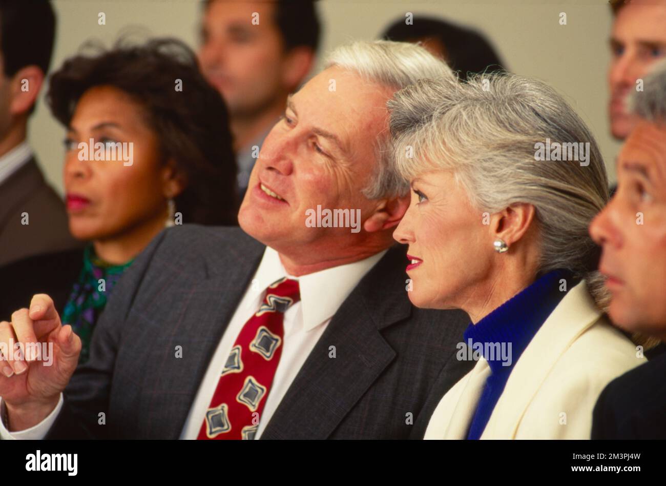 Older couple sitting in a crowd at a meeting Stock Photo - Alamy