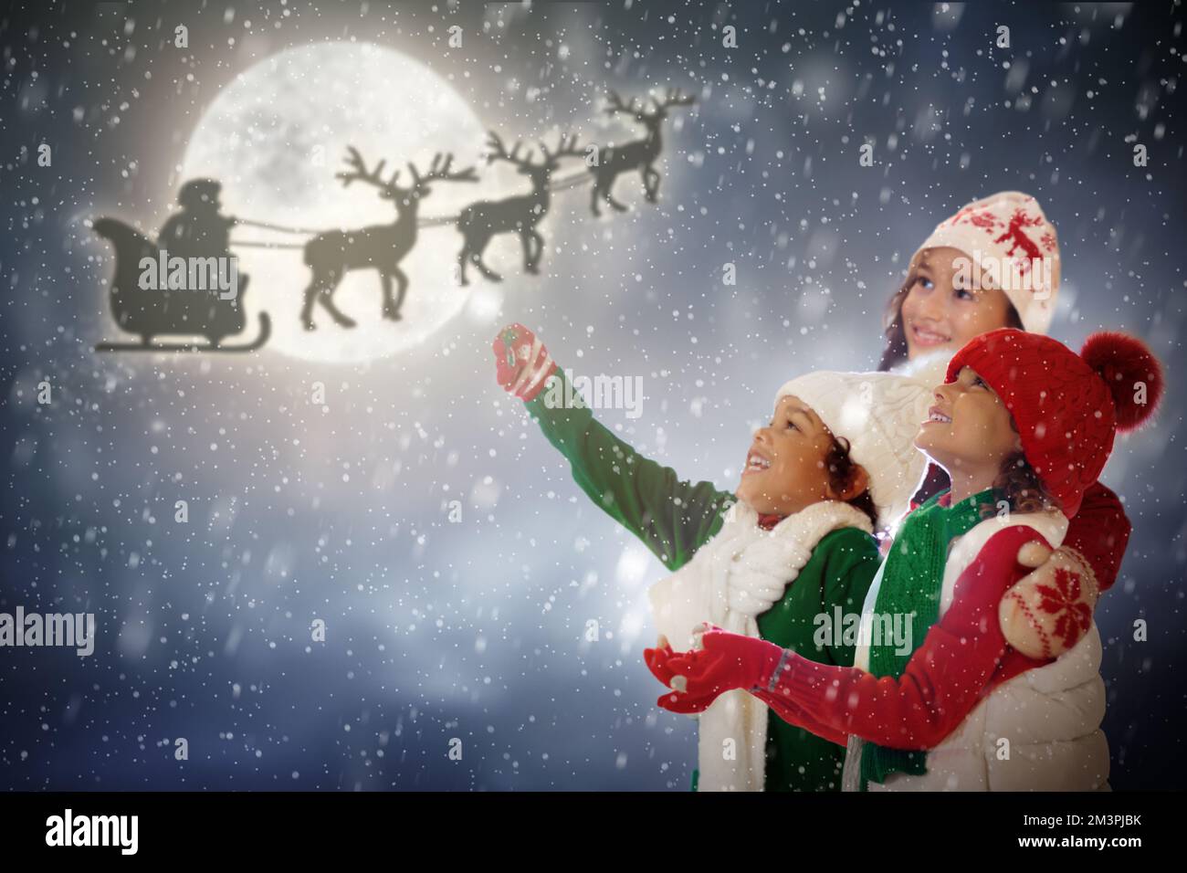 Kids look at Santa fly in the sky on Christmas eve. Children watch reindeer and Santa Claus ...