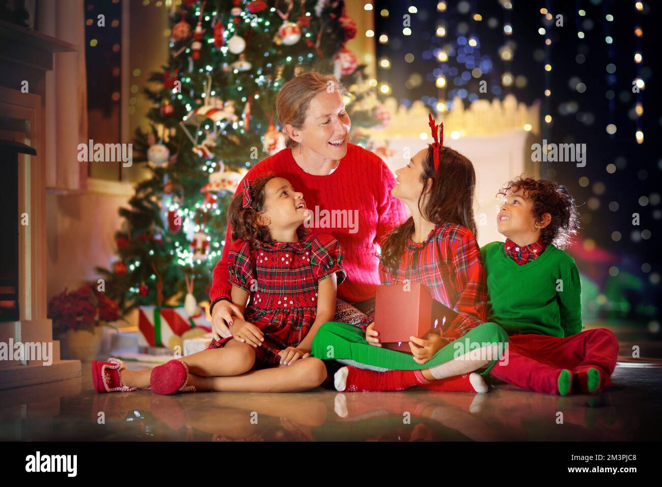Family under a Christmas tree. Mother and kids with gifts in decorated ...