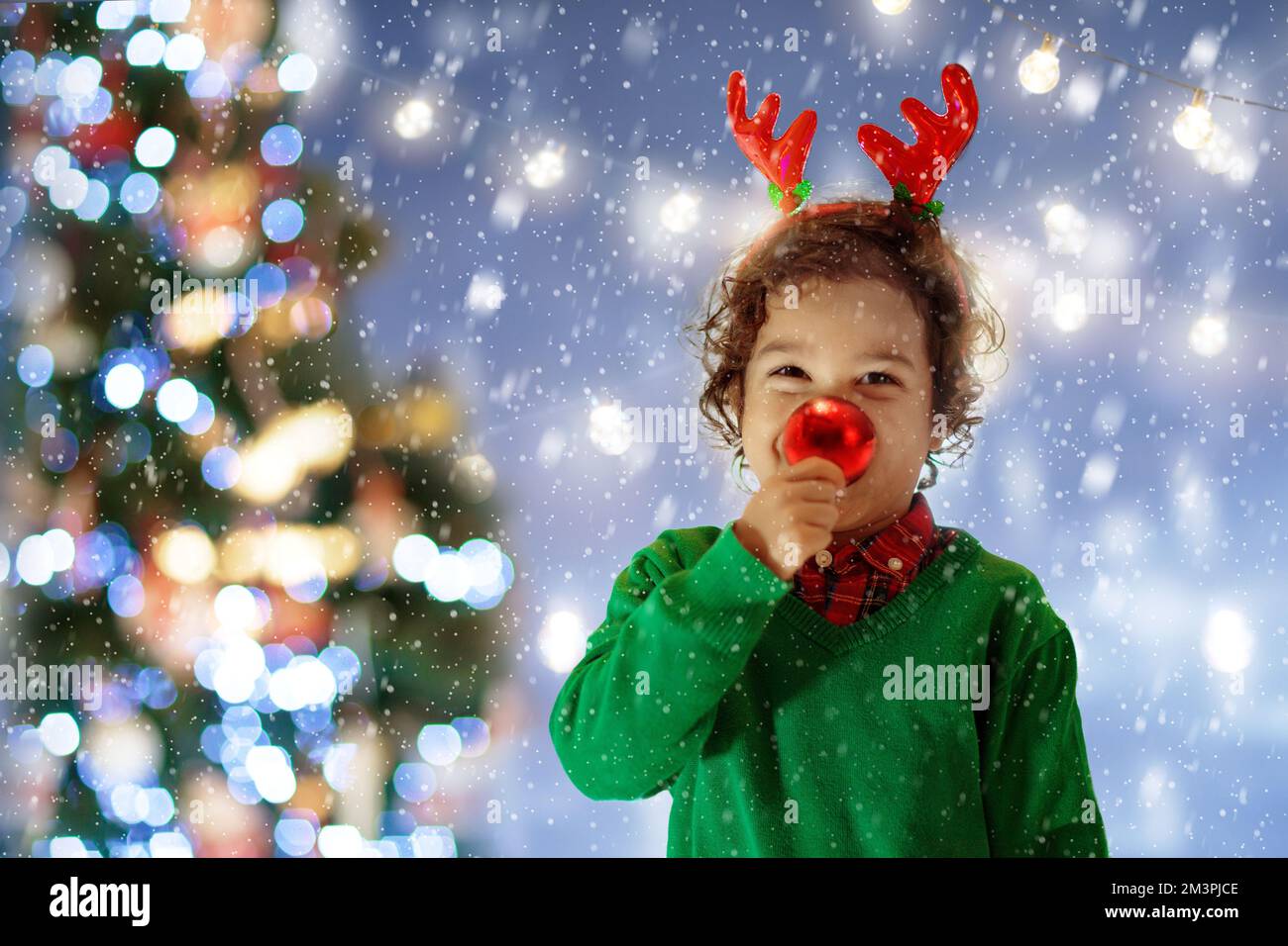Child with reindeer nose and antlers on Christmas eve. Little boy ...