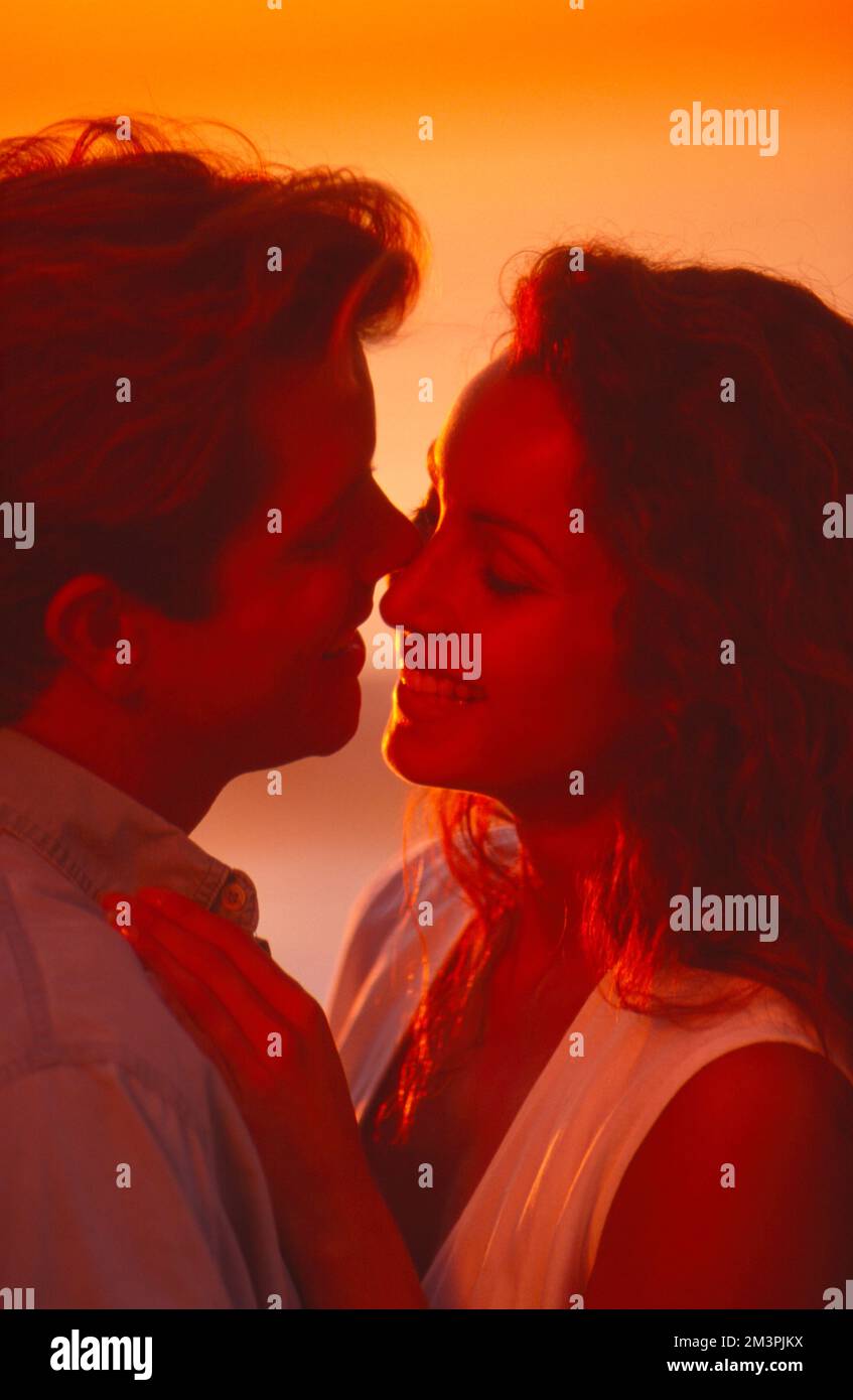 Younger couple being intimate, embracing against a warm sunset Stock ...