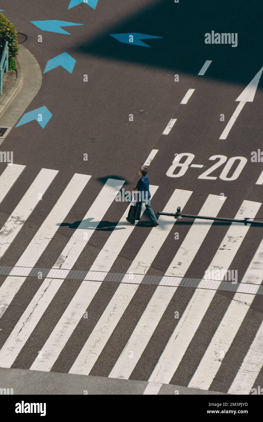 A single person crossing the road on a sunny day in Tokyo, Japan Stock ...