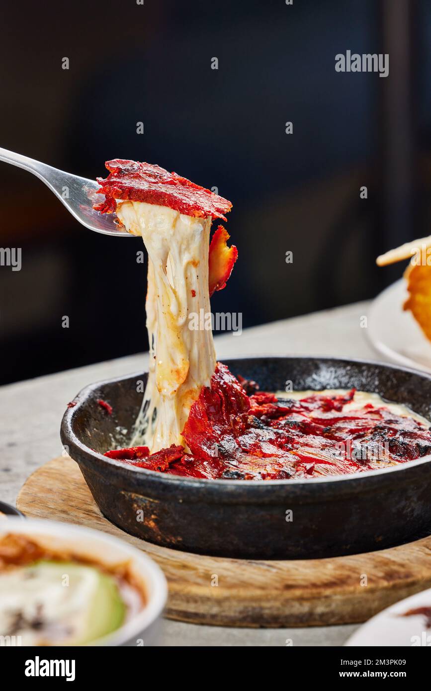 A vertical closeup of a chef cutting a Chicago-style pizza in a pan ...