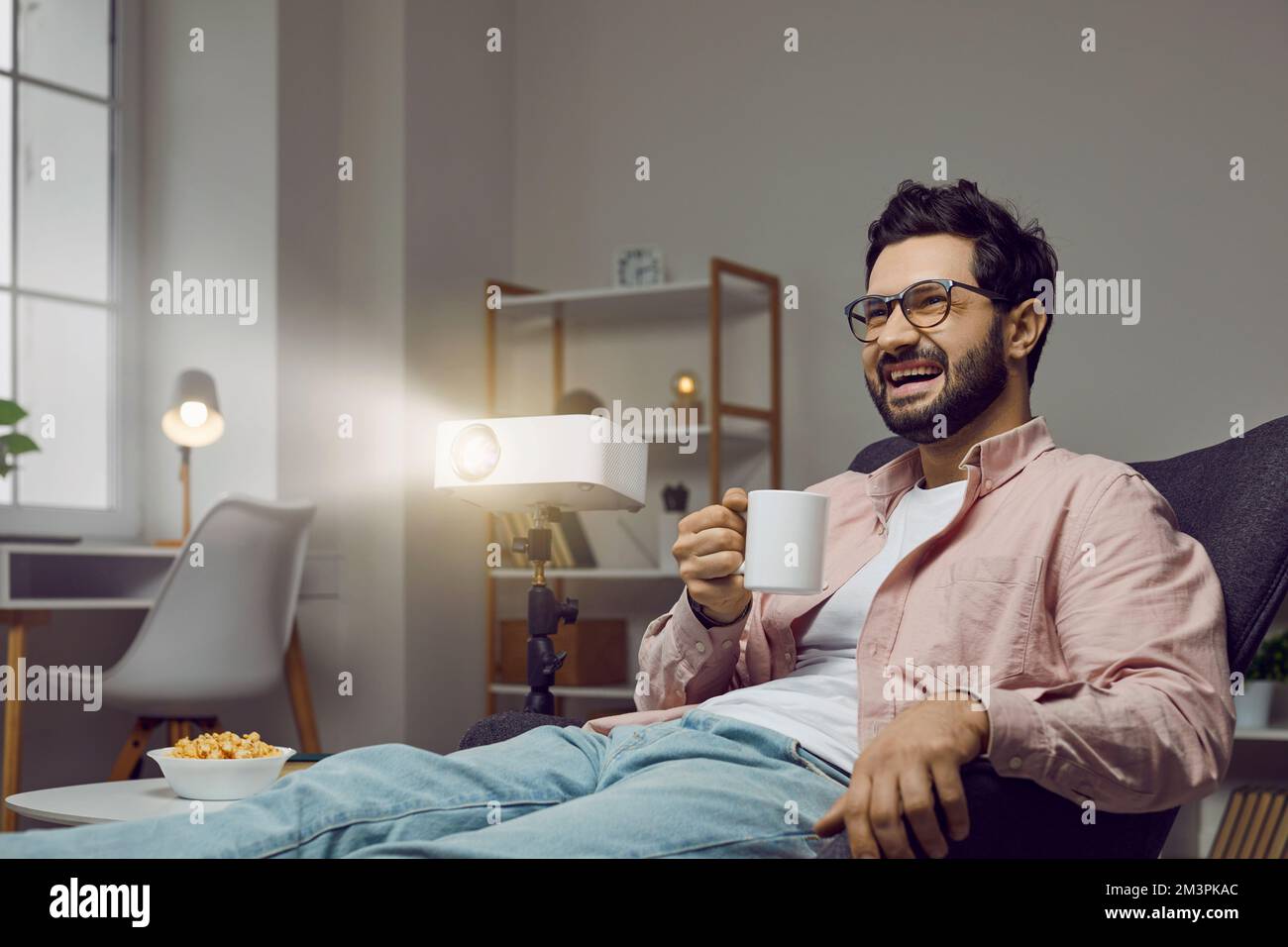 Cheerful man is watching comedy movie alone at home with help of movie ...