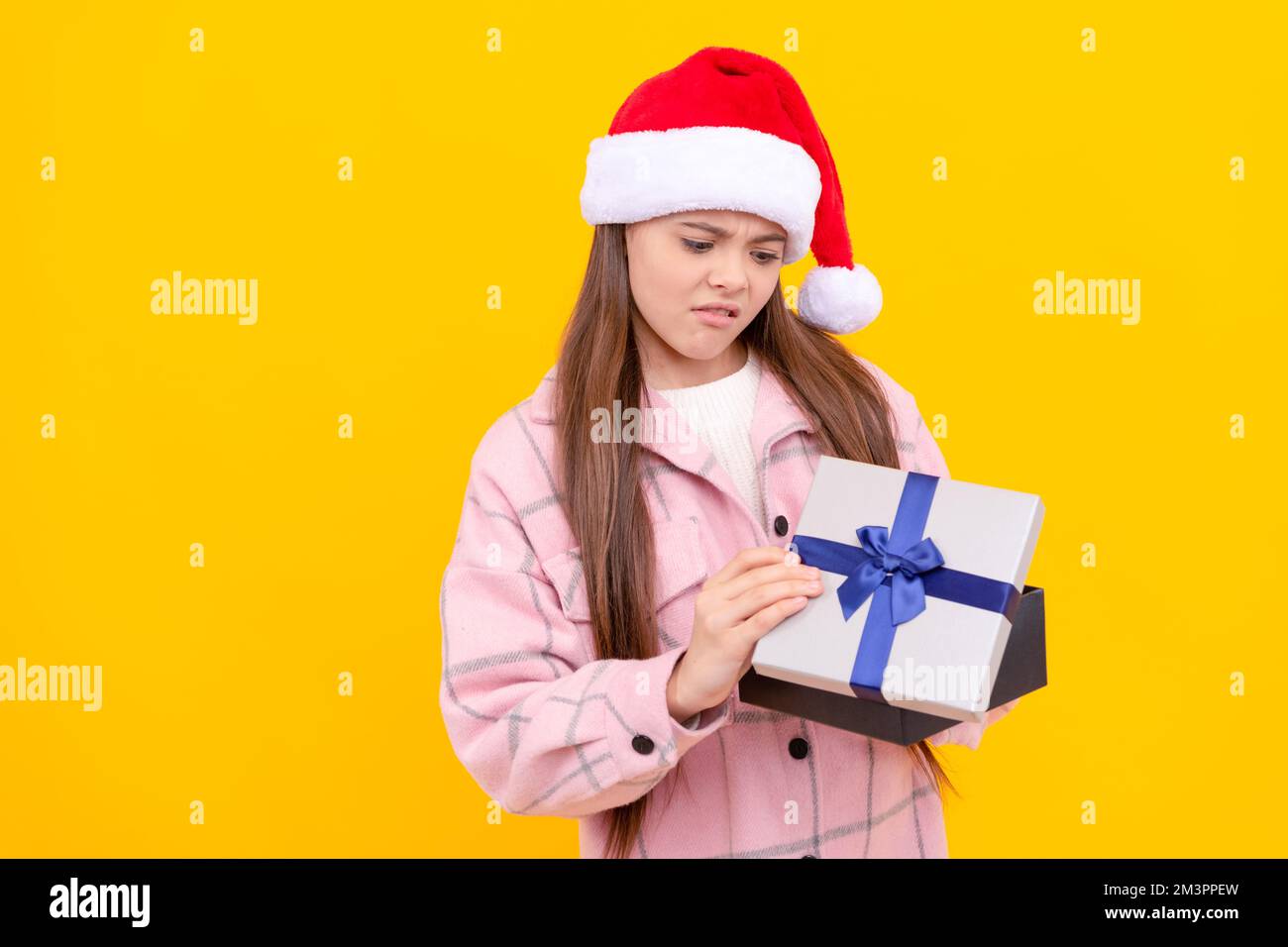 confused kid in santa claus hat hold gift box on yellow background ...