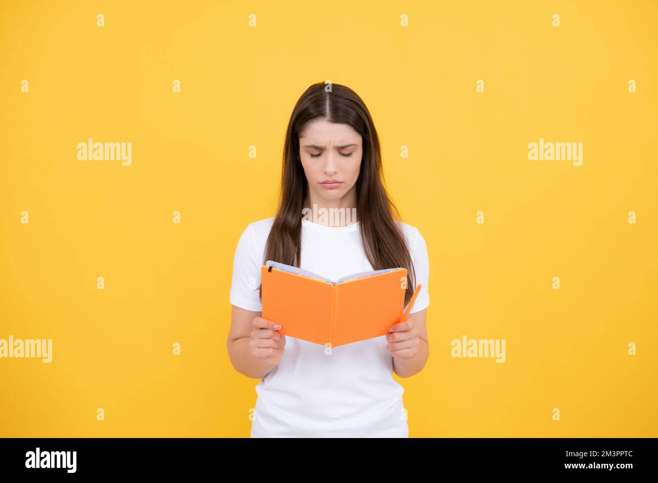 Sad angry young woman college student holding book on isolated gray ...