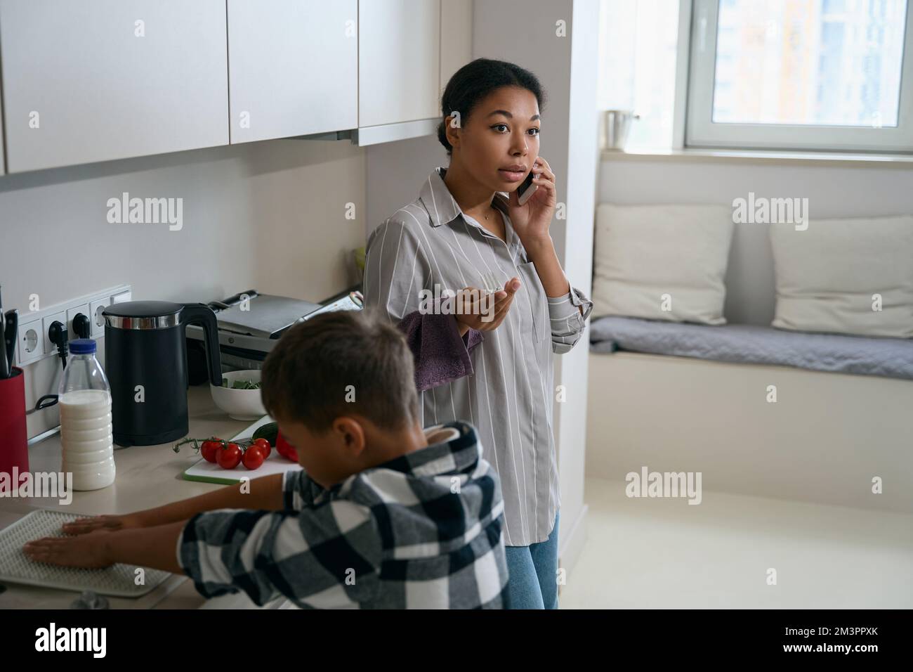 Beautiful African female is having conversation on smartphone at home ...