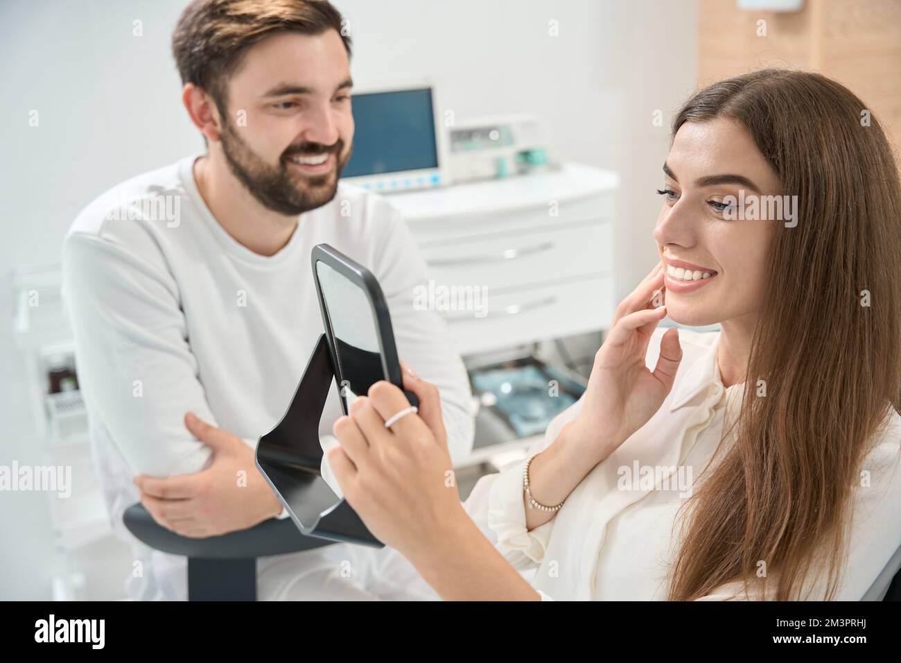 Pleased dental clinic client admiring her anterior teeth after ...