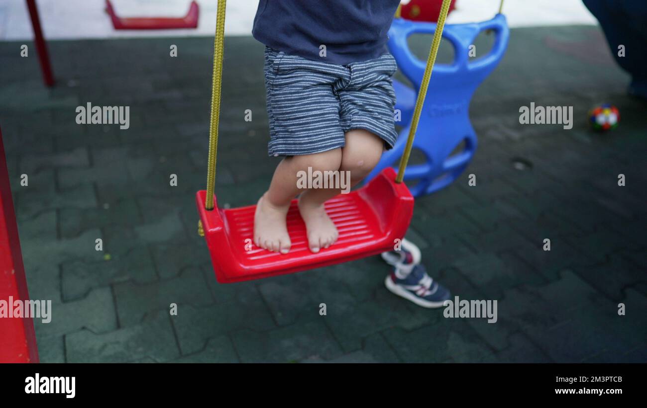 Child standing on playground swing carefree kid playing Stock Photo - Alamy