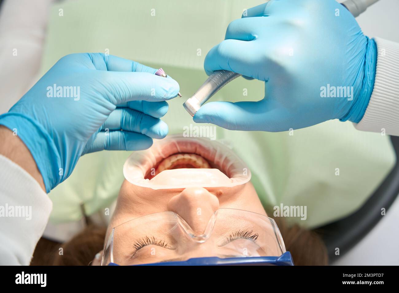 Dentist preparing to carry out teeth-polishing procedure on female ...
