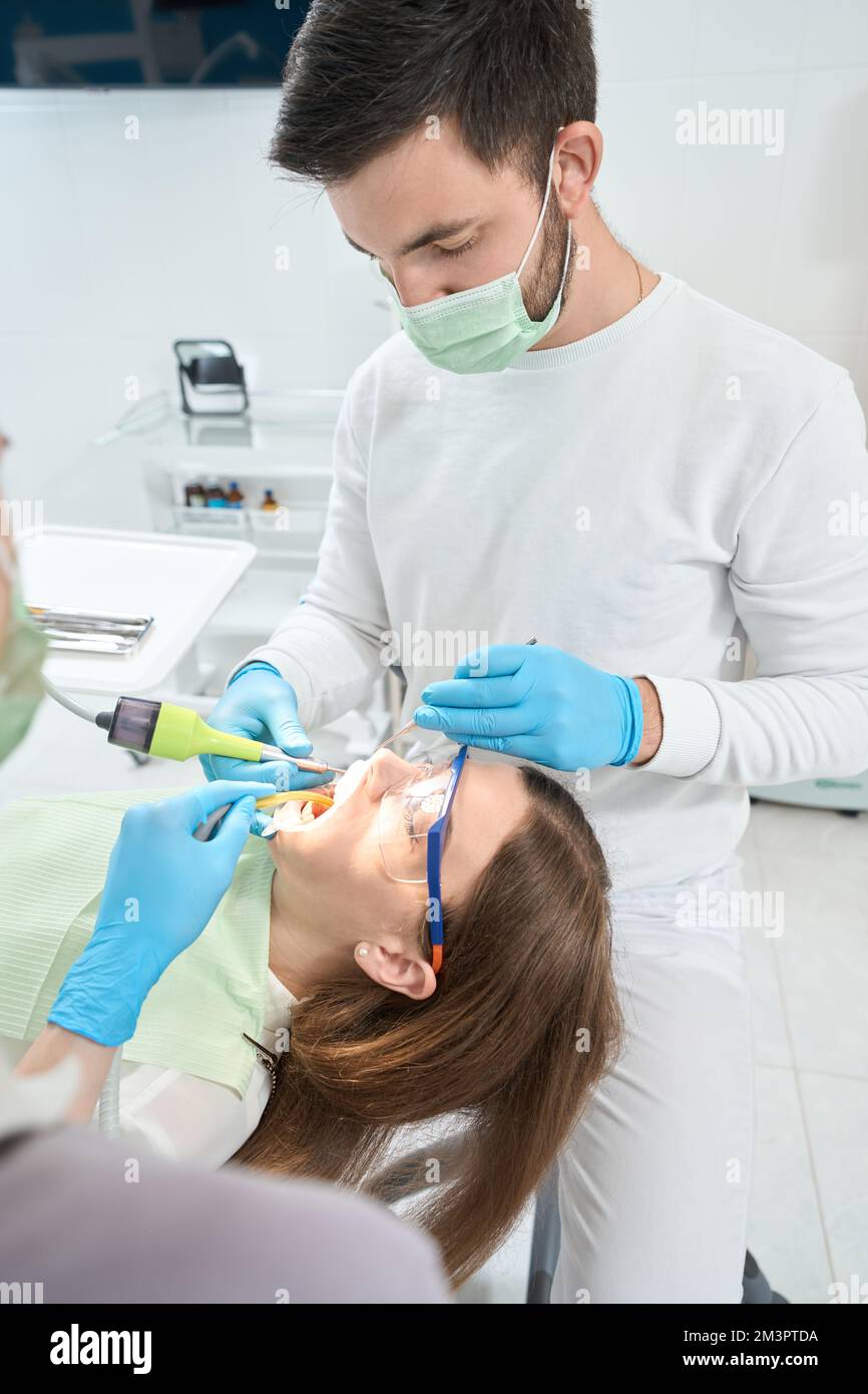 Doctor treating caries in young woman assisted by nurse Stock Photo - Alamy