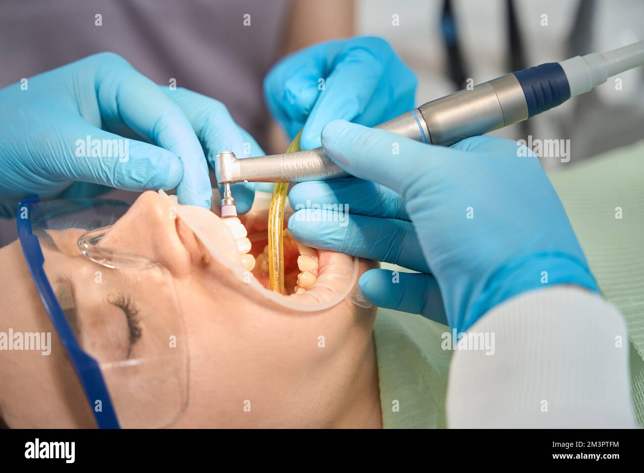Dental conducting teeth-polishing procedure on client assisted by nurse ...