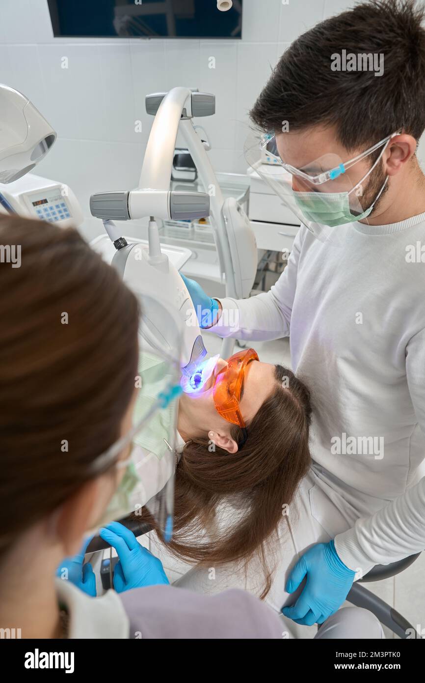 Professional dentist performing teeth-whitening procedure on patient ...