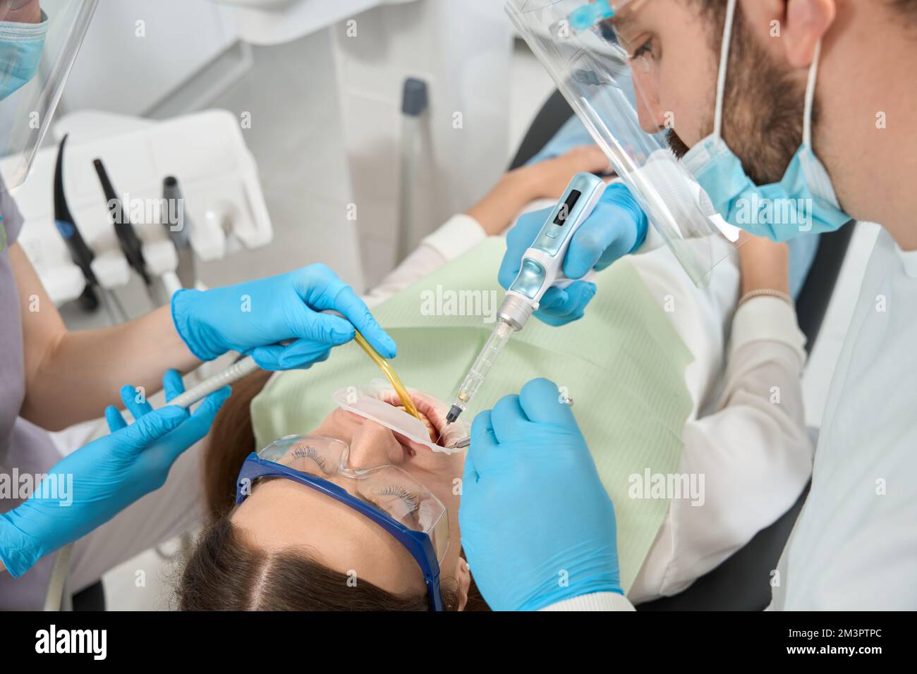 Focused doctor administering local anesthesia to young woman Stock ...