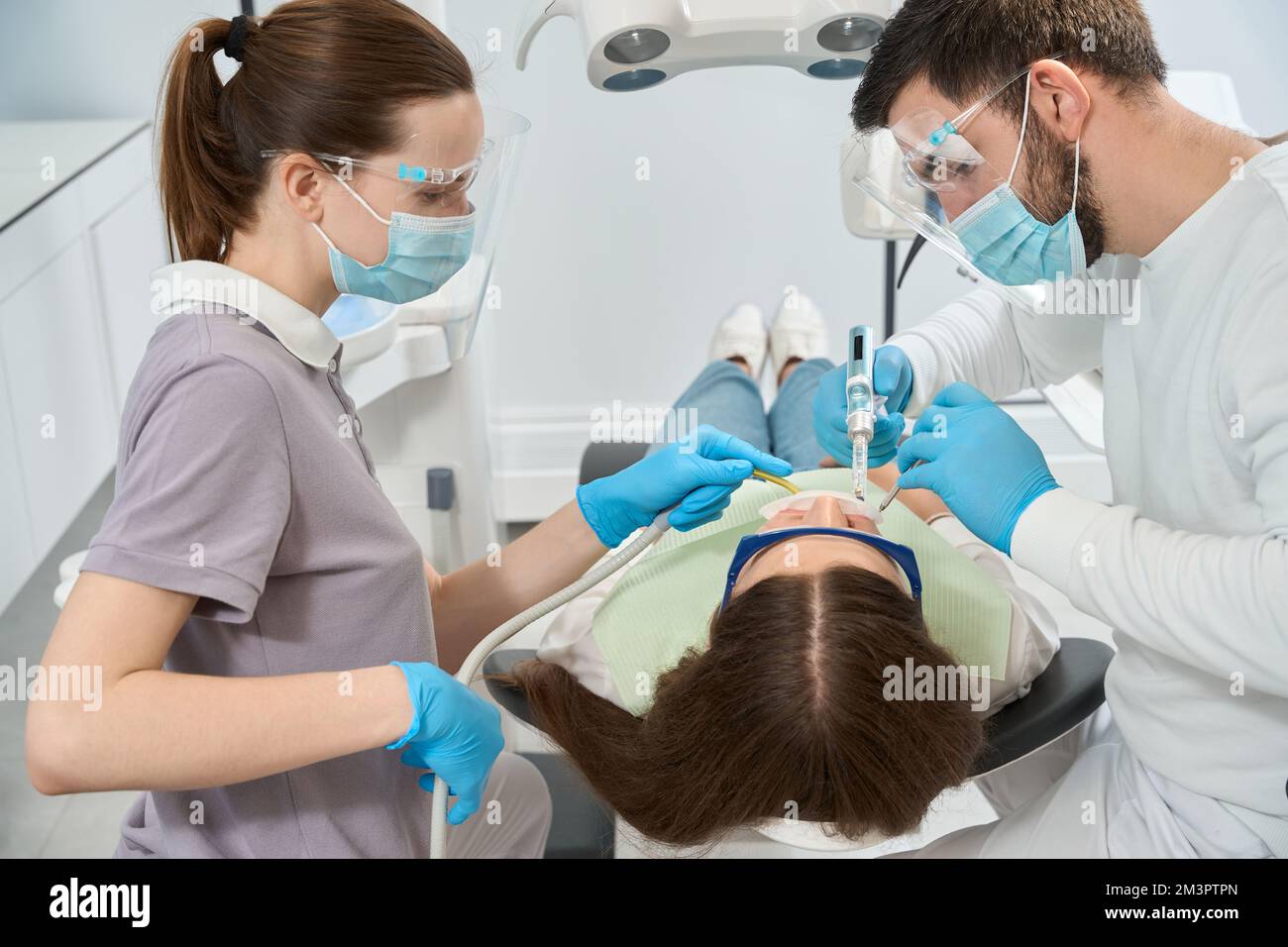 Male dentist is giving anesthesia to woman aided by assistant Stock ...