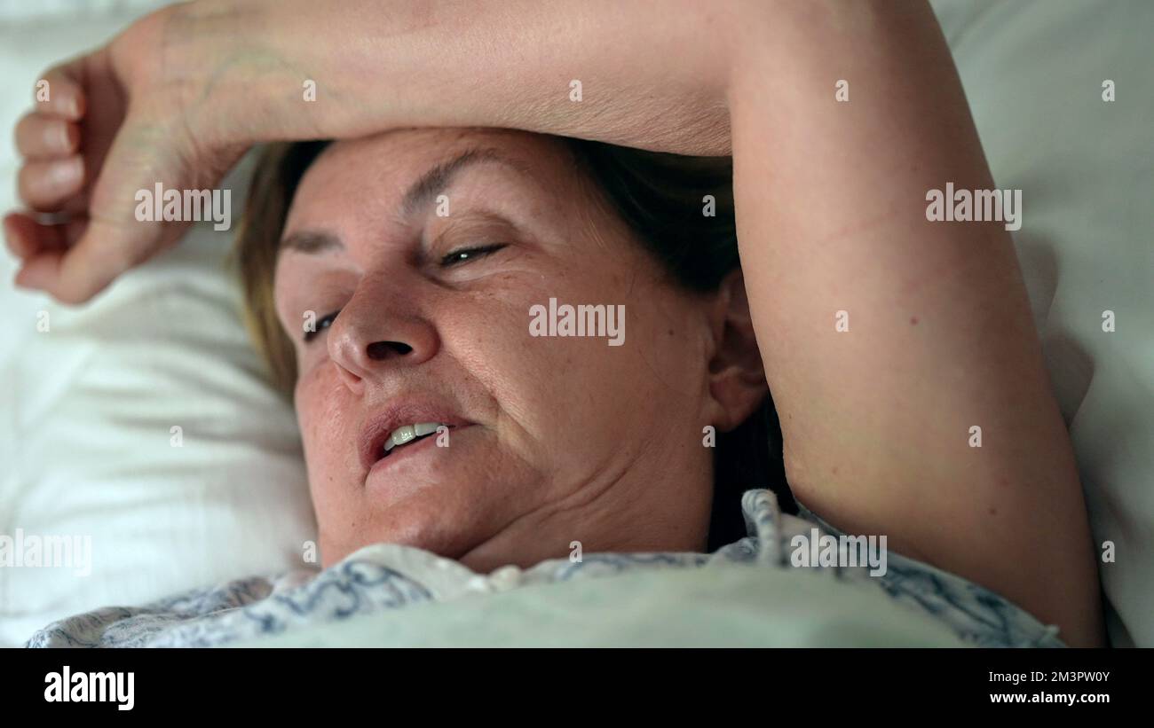 Tired older person waking up senior woman getting up from bed in ...