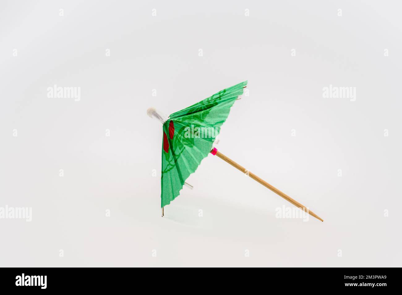 Single green cocktail parasol umbrella isolated on a white background ...