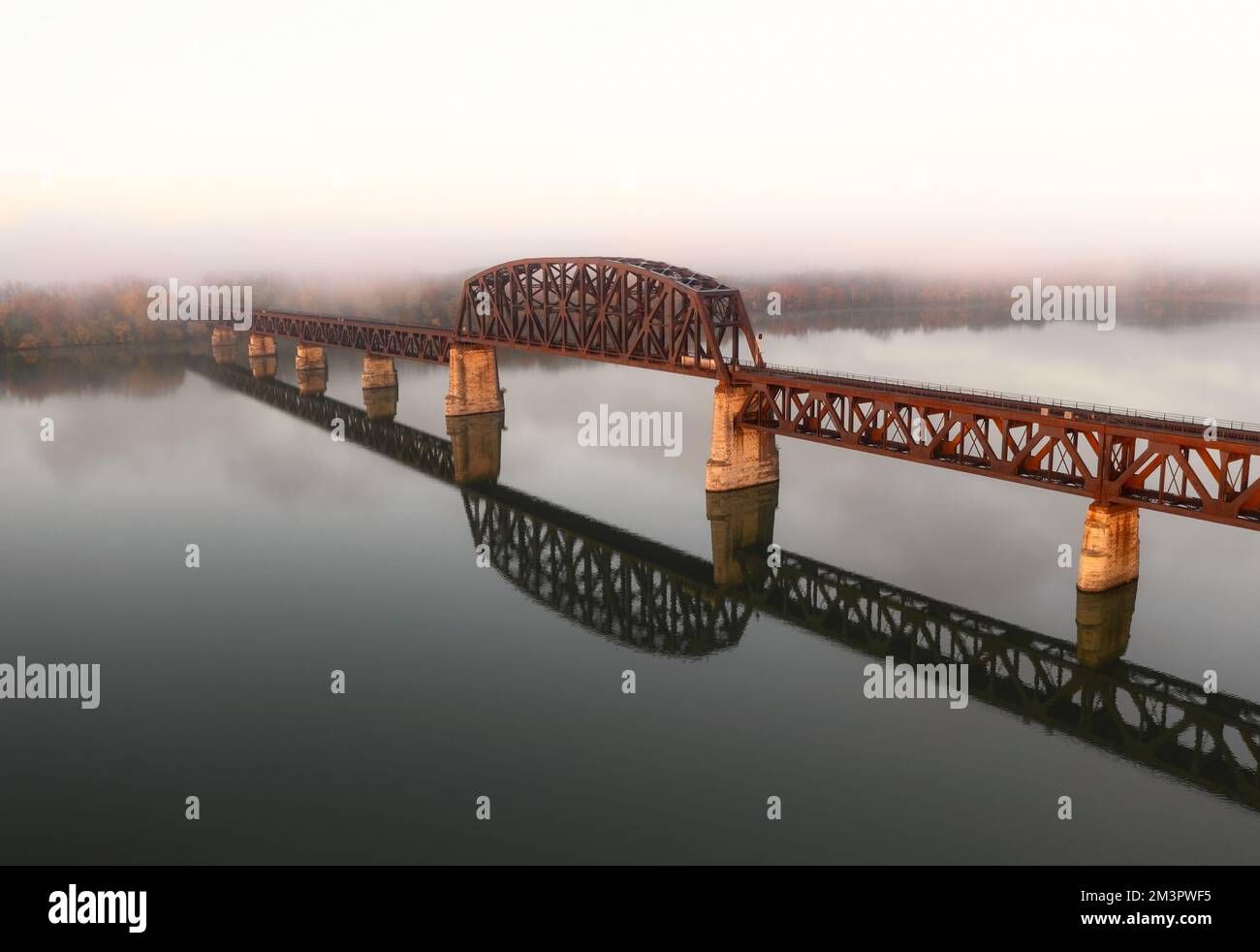 An aerial view of Ohio railroad bridge over a river at foggy sunrise ...