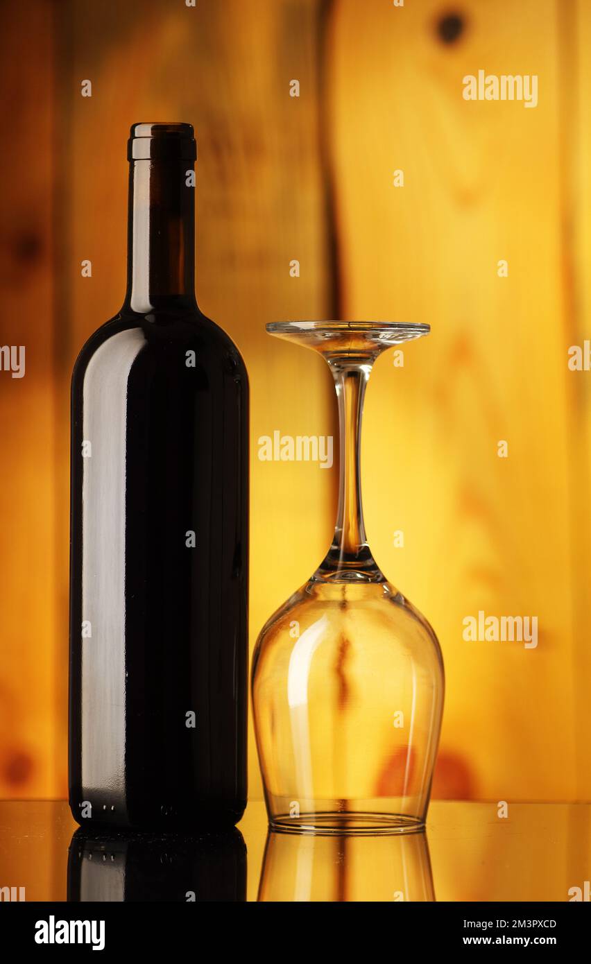 bottle with wine and an inverted glass on a background of wooden boards ...