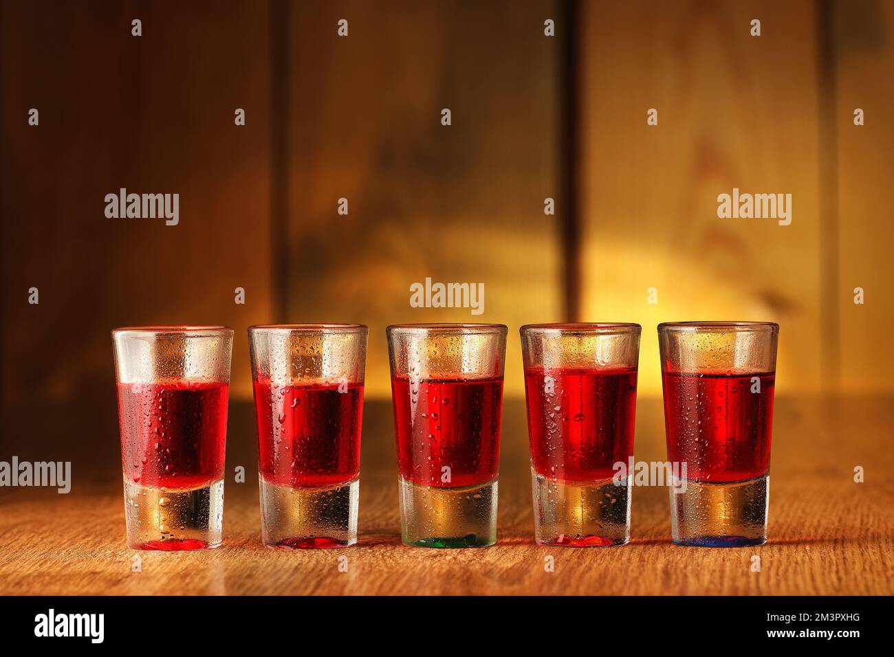 five glasses with cranberry vodka on a background of wooden boards ...