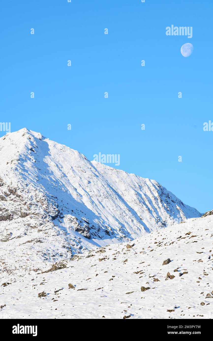 Moon above Snowdon mountain summit range on a day with a clear blue sky ...