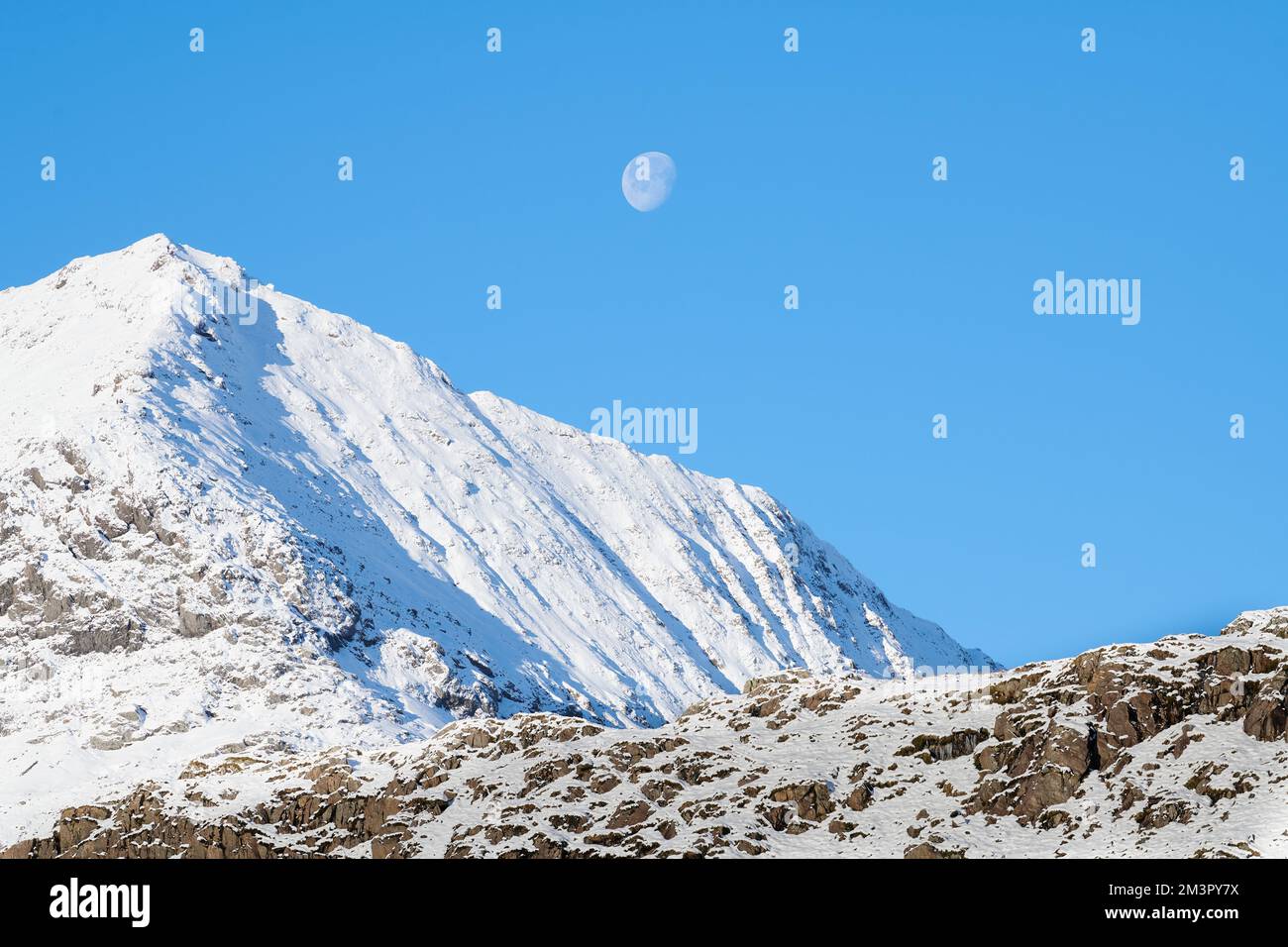Moon above Snowdon mountain summit range on a day with a clear blue sky ...