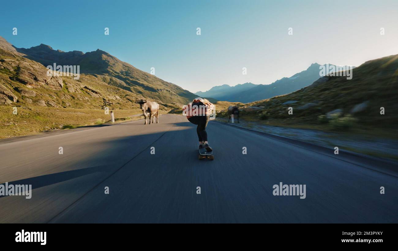 Cinematic downhill longboard session. Young woman skateboarding and ...