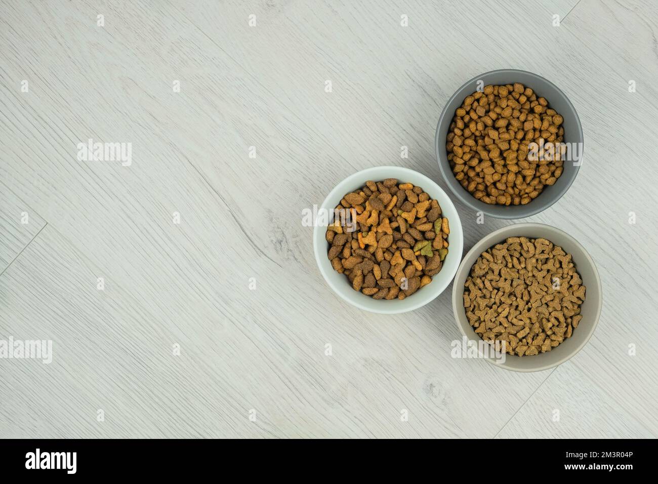 Dry food for cats and dogs in bowls on a white wooden background. Top ...