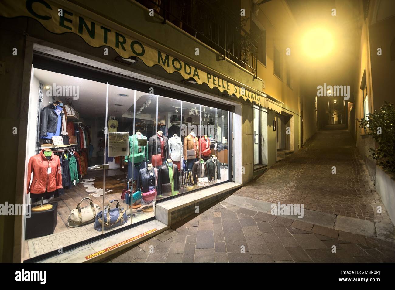 Cobbled narrow street with lit shop windows at night Stock Photo - Alamy