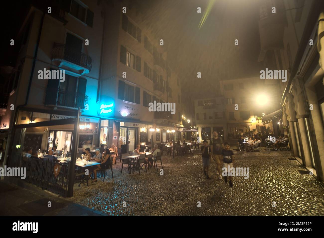 Square with restaurant and people dining at night Stock Photo - Alamy