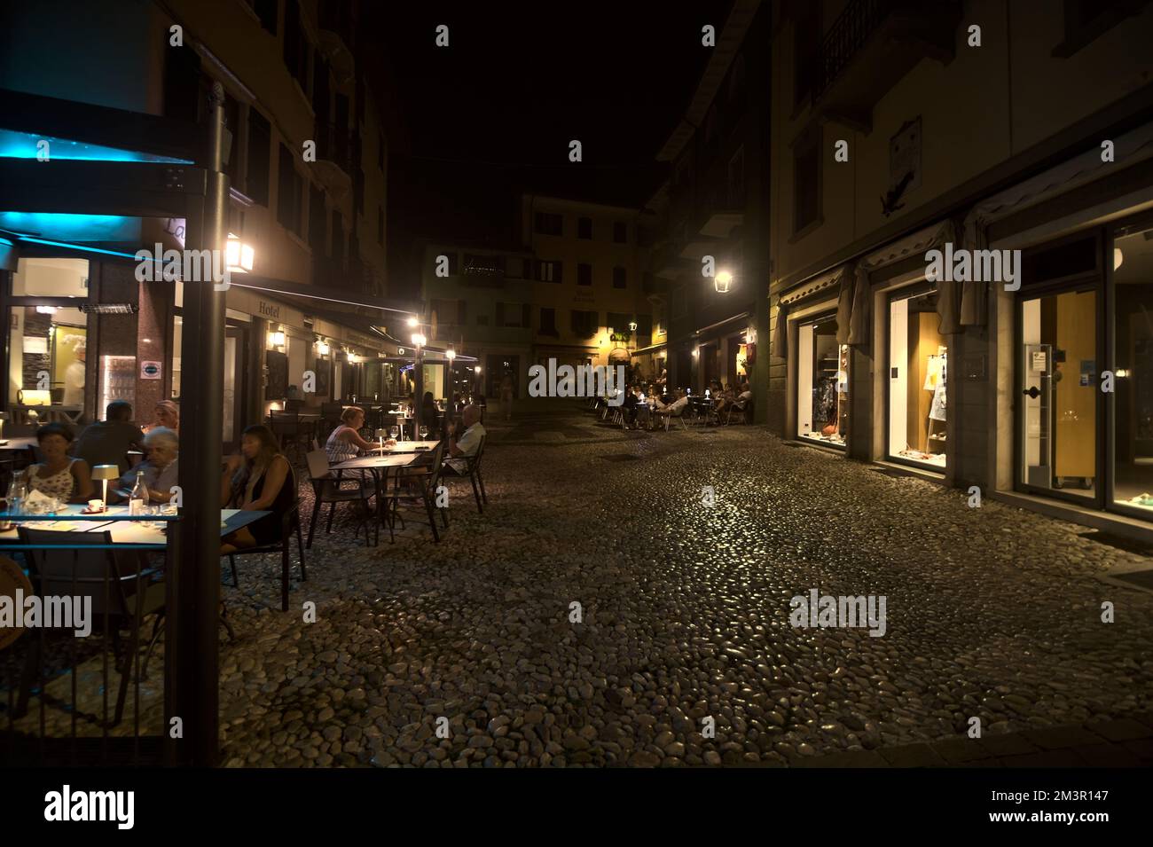 Square with restaurant and people dining at night Stock Photo - Alamy