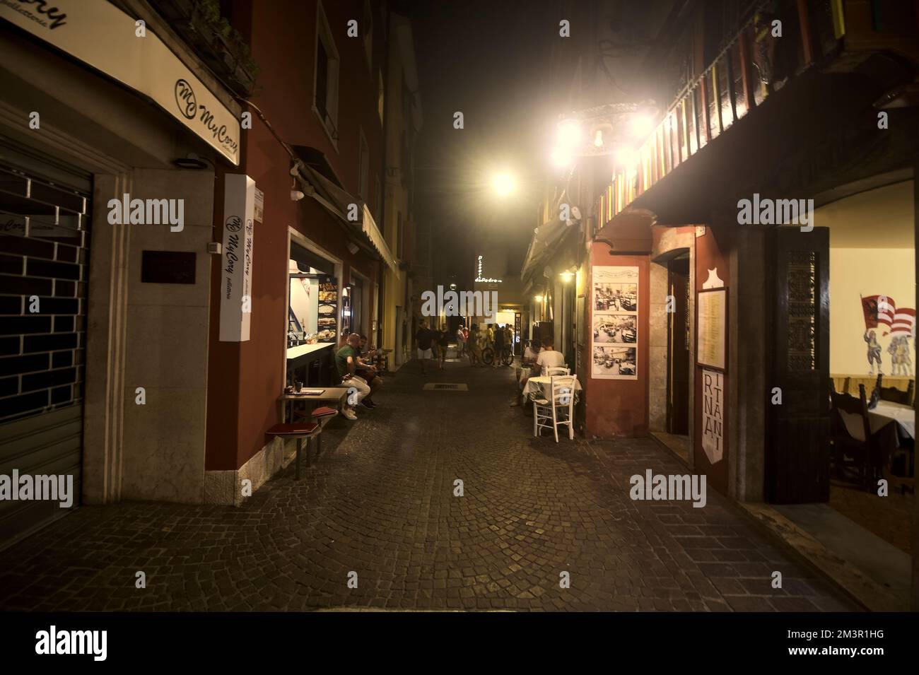 Square with restaurant and people dining at night Stock Photo - Alamy
