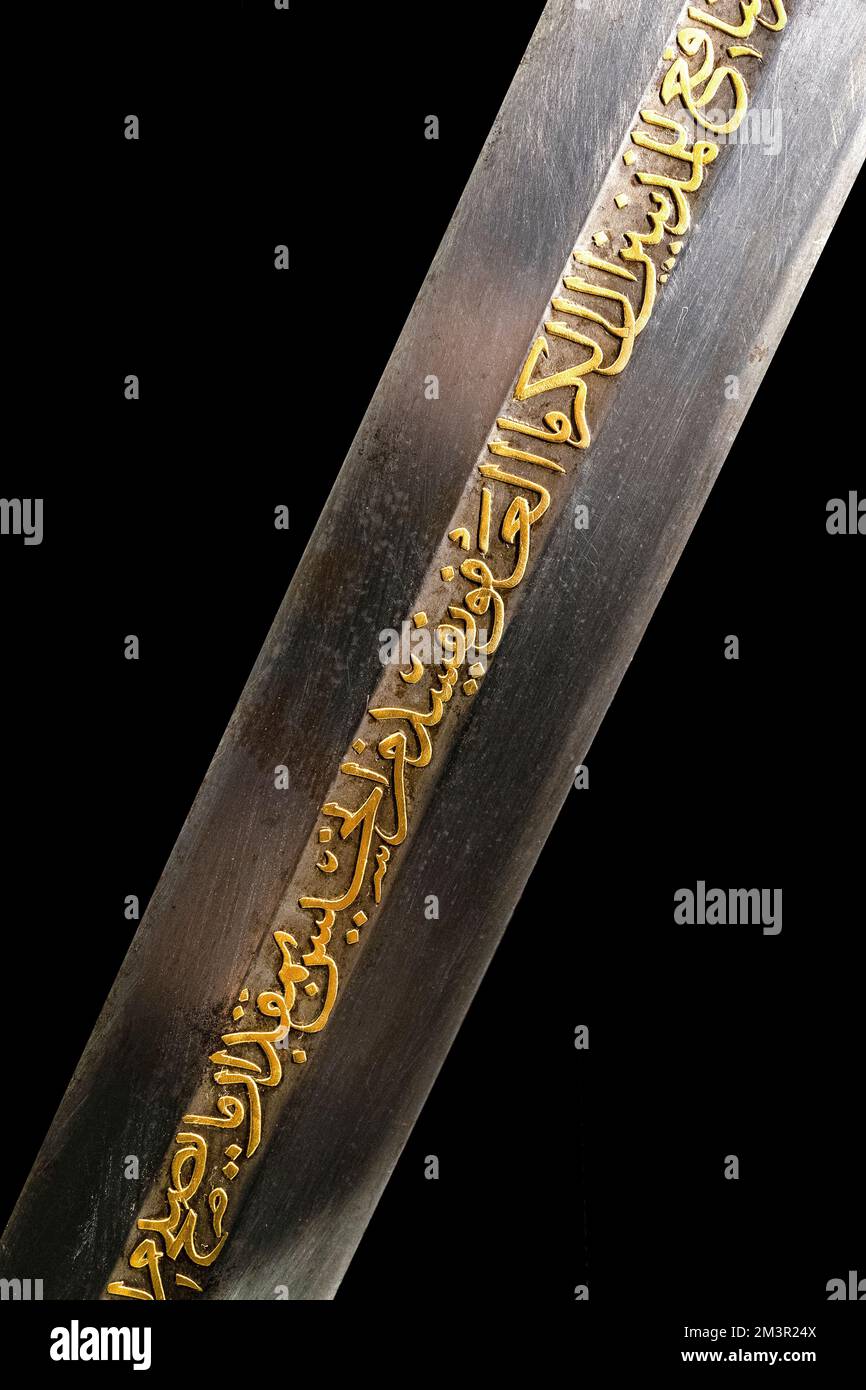 A closeup of a sword surface with Arabic words isolated on a black ...