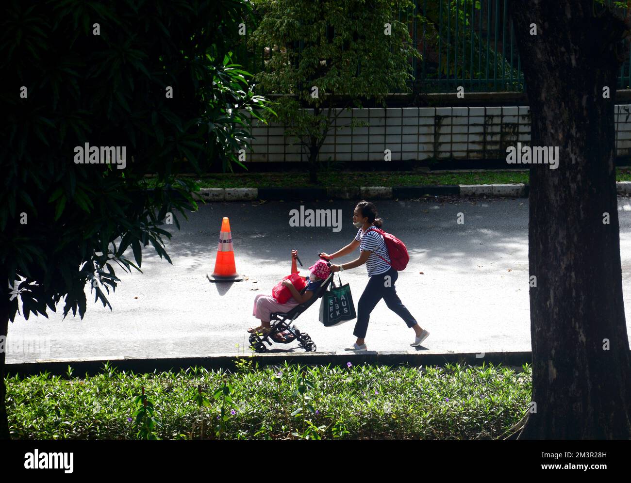 a woman walking while pushing a baby in her stroller Stock Photo - Alamy