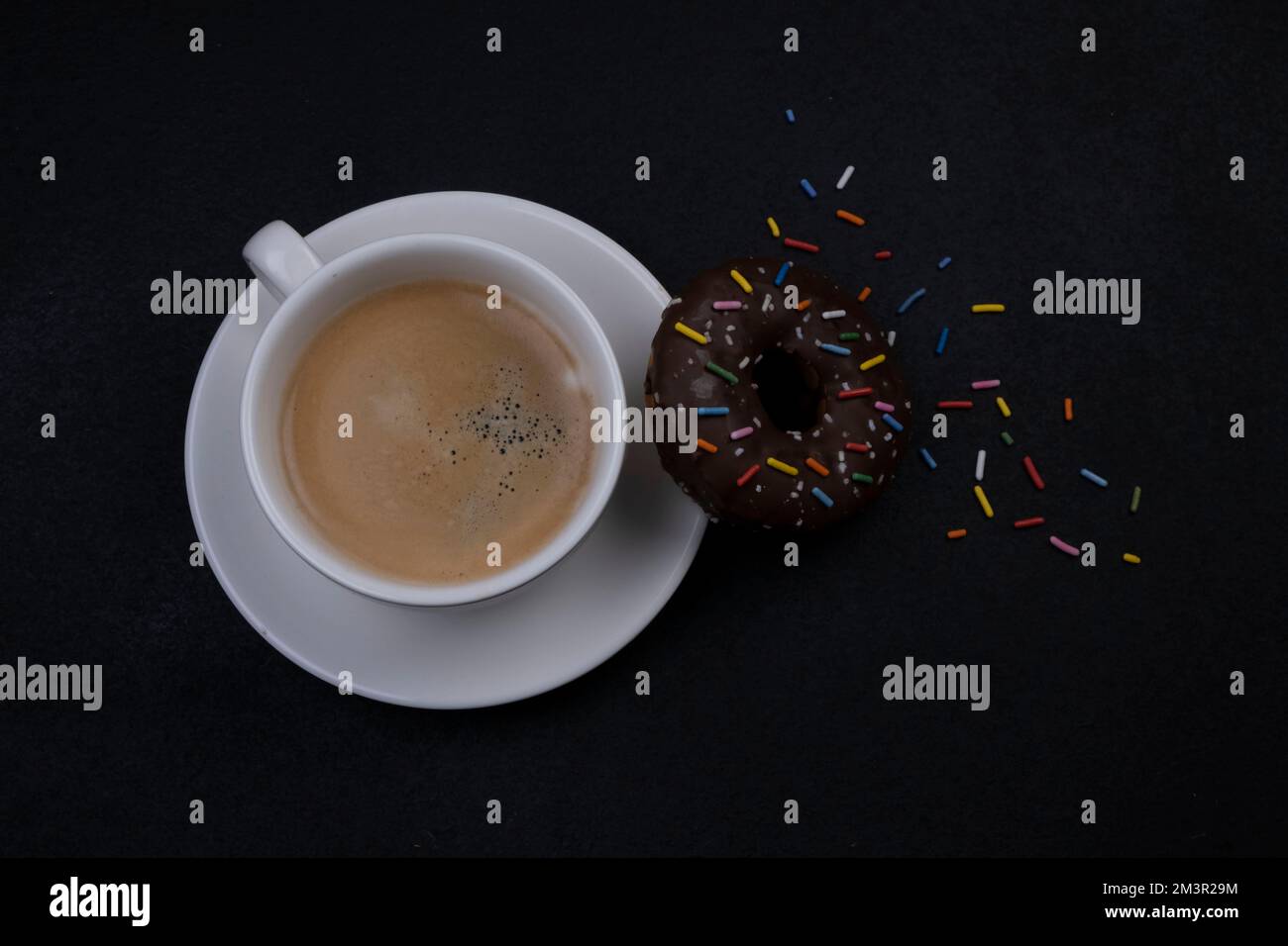 takes coffee with a chocolate donut and multi-colored sprinkles on a ...