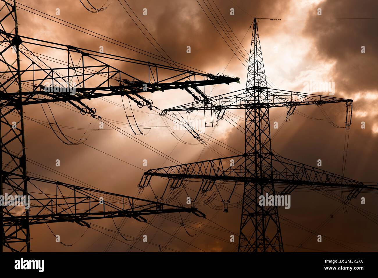 high voltage pylons for electricity and power against sky with dramatic ...