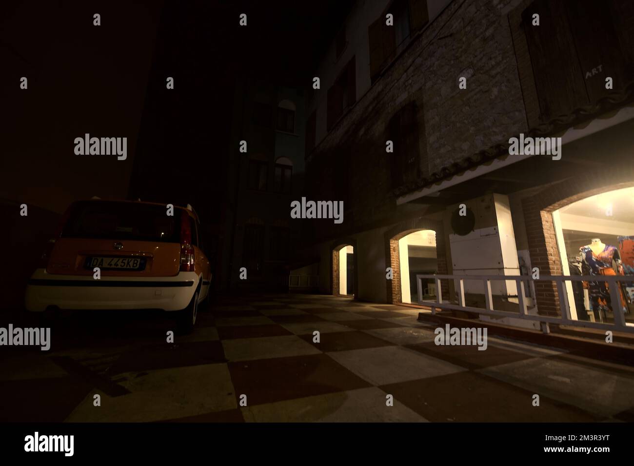 Cobbled narrow street with lit shop windows at night Stock Photo - Alamy