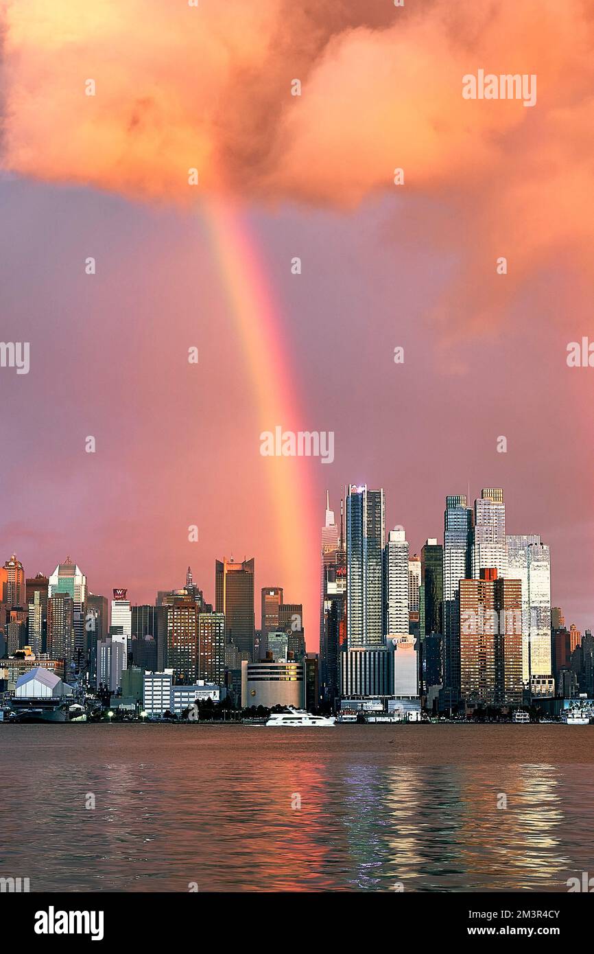 A vertical shot of a scenic sunset sky with a rainbow over the ...
