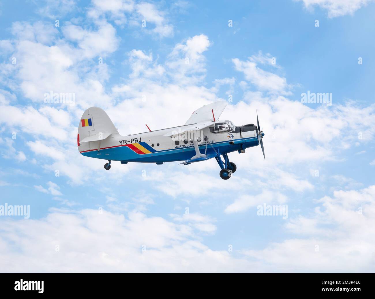 A soviet Antonov An-2 single-engine biplane flying against blue sky ...