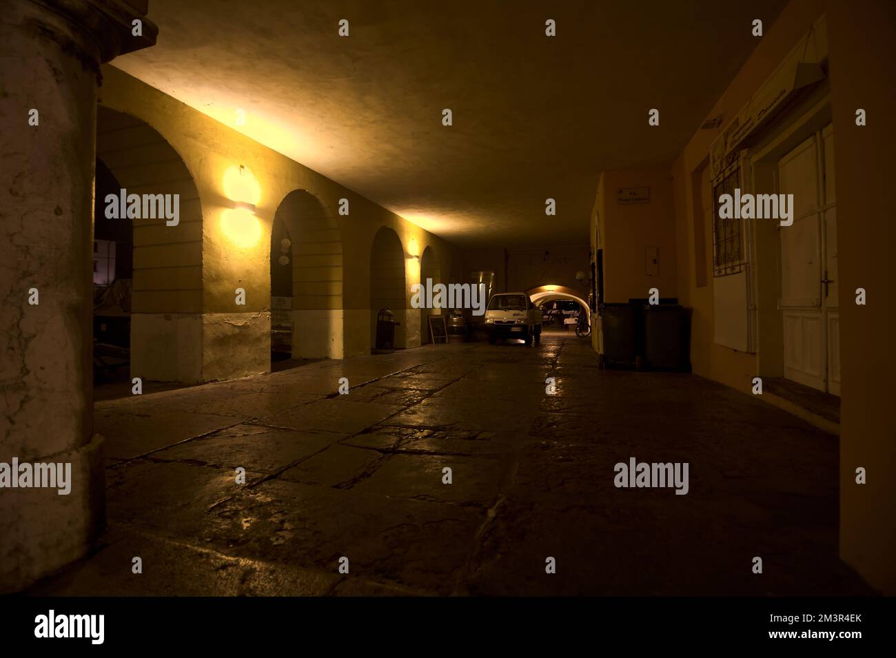 Covered alleyway with closed shops and a parked car at night Stock ...