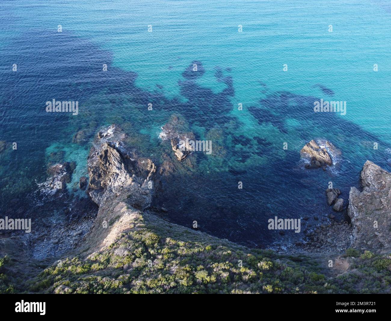 A cliff side of Ostriconi beach with dark outlines in water Stock Photo ...