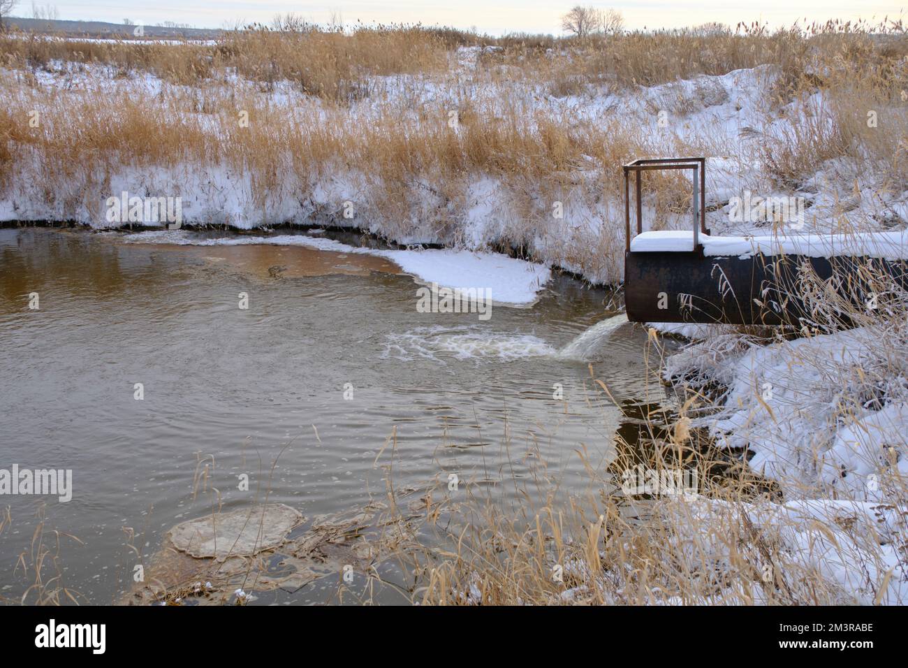 Sewage discharge from pipe into river in winter, river pollution and ...