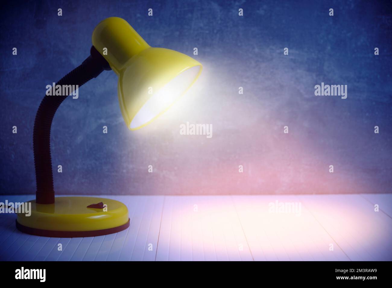 Bright yellow desk lamp turned on against lighted concrete wall Stock ...