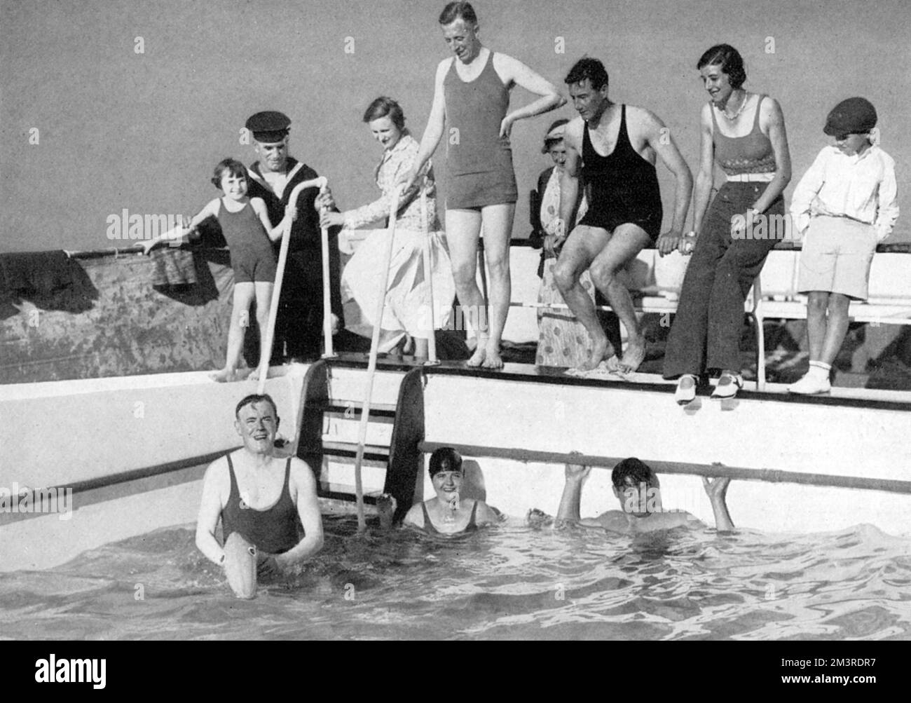Passengers on board a cruise liner cool off in a bathing pool on deck ...