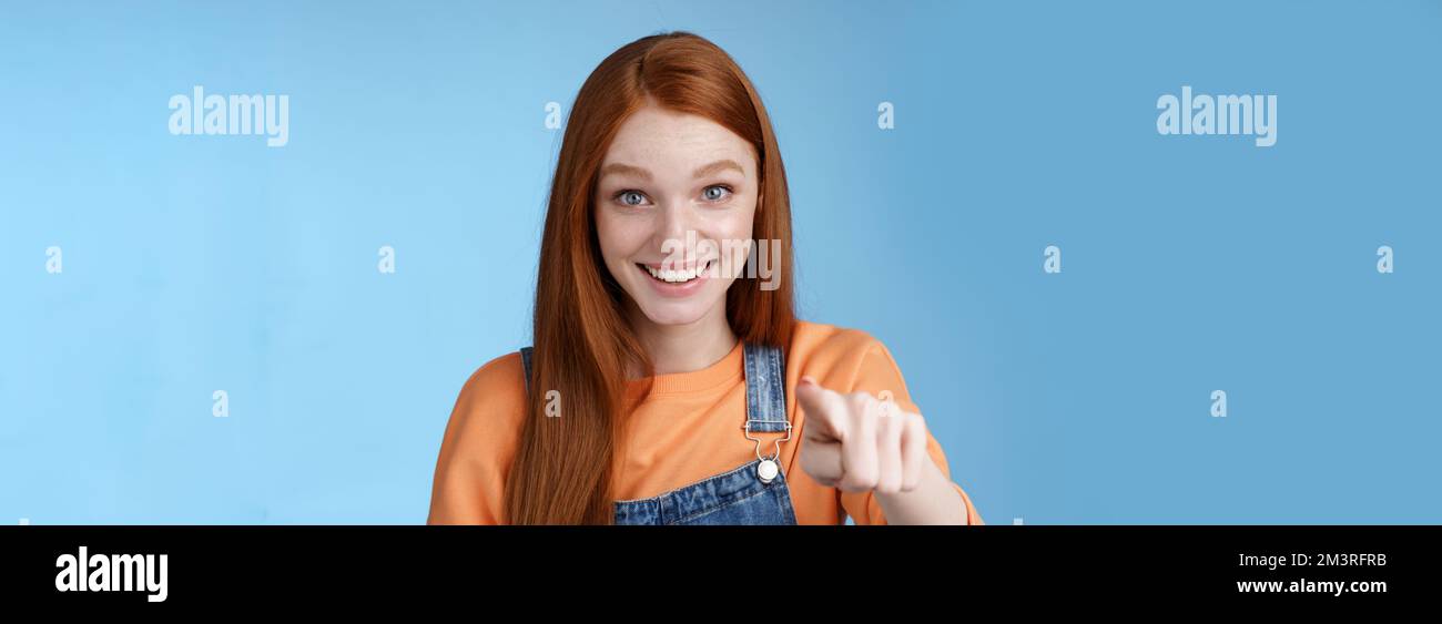 Impressed surprised young cute girl pointing camera amazed wide eyes ...