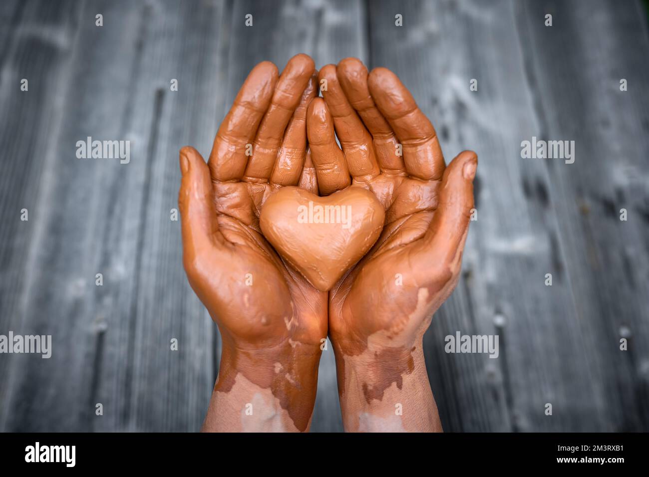 Heart made of potter's clay in the hands of a master potter. Love ...