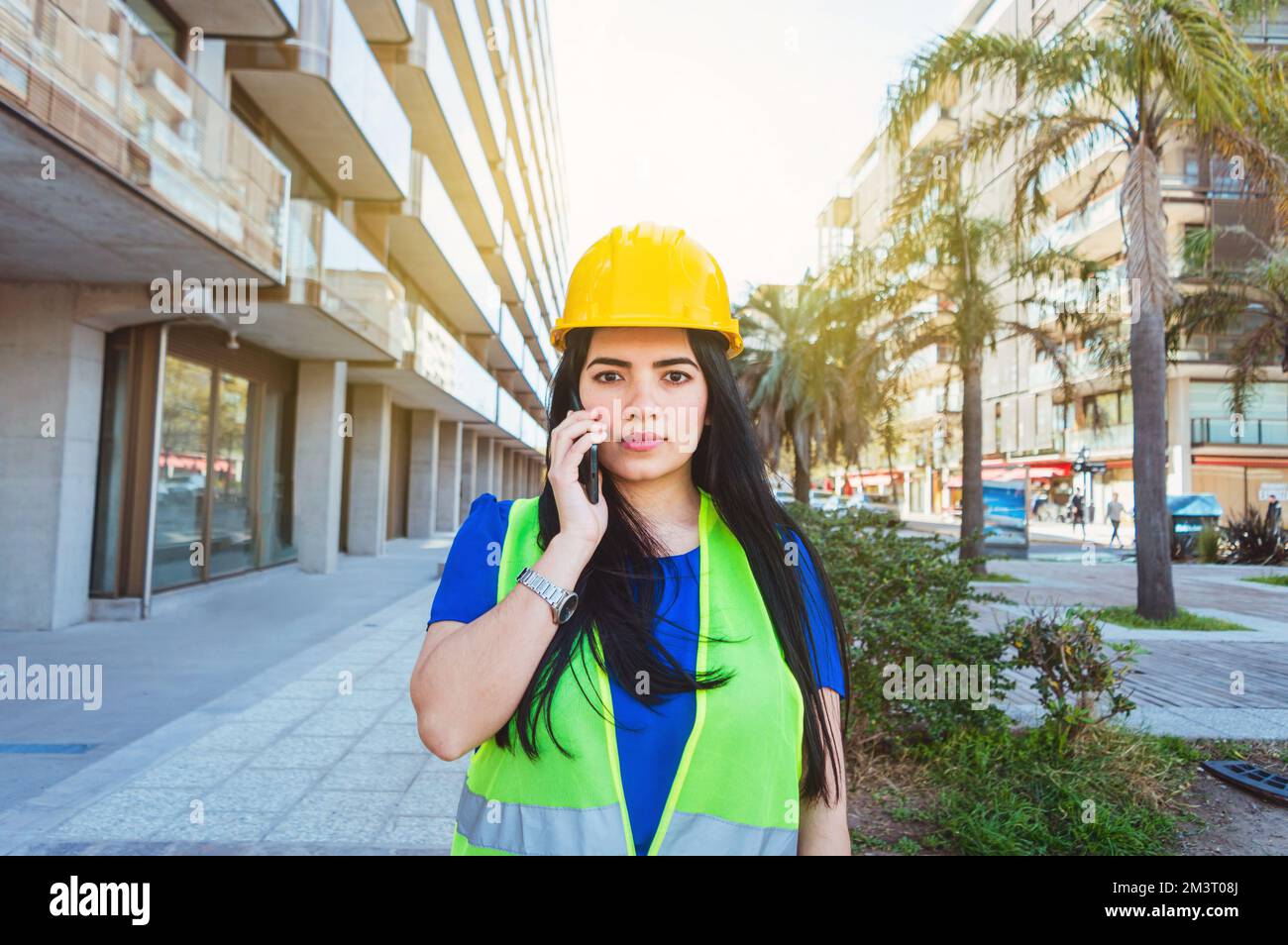 front view of young caucasian female construction worker wearing yellow safety helmet and safety ...
