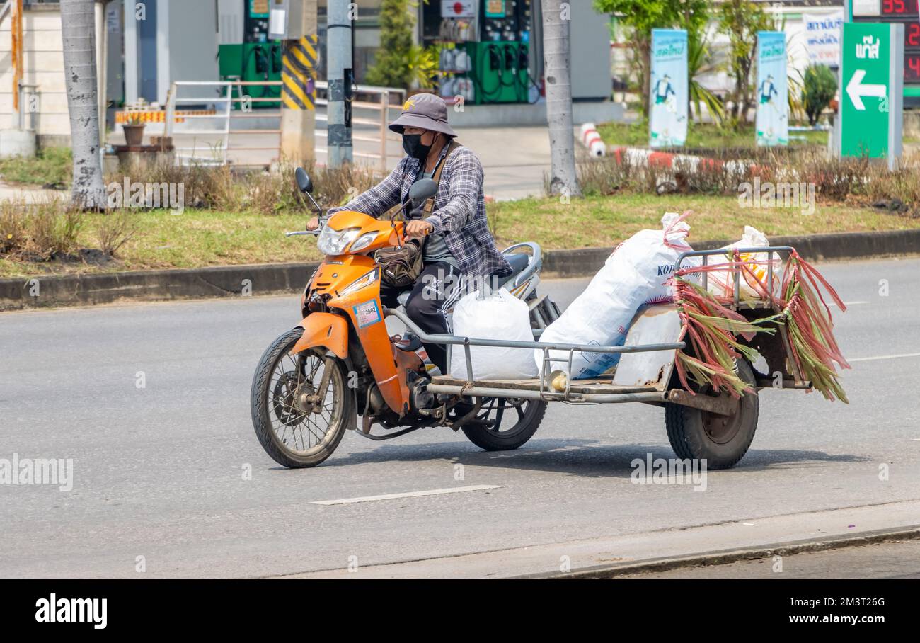 RATCHABURI, THAILAND, NOV 16 2022, A man drives a motorcycle with an ...