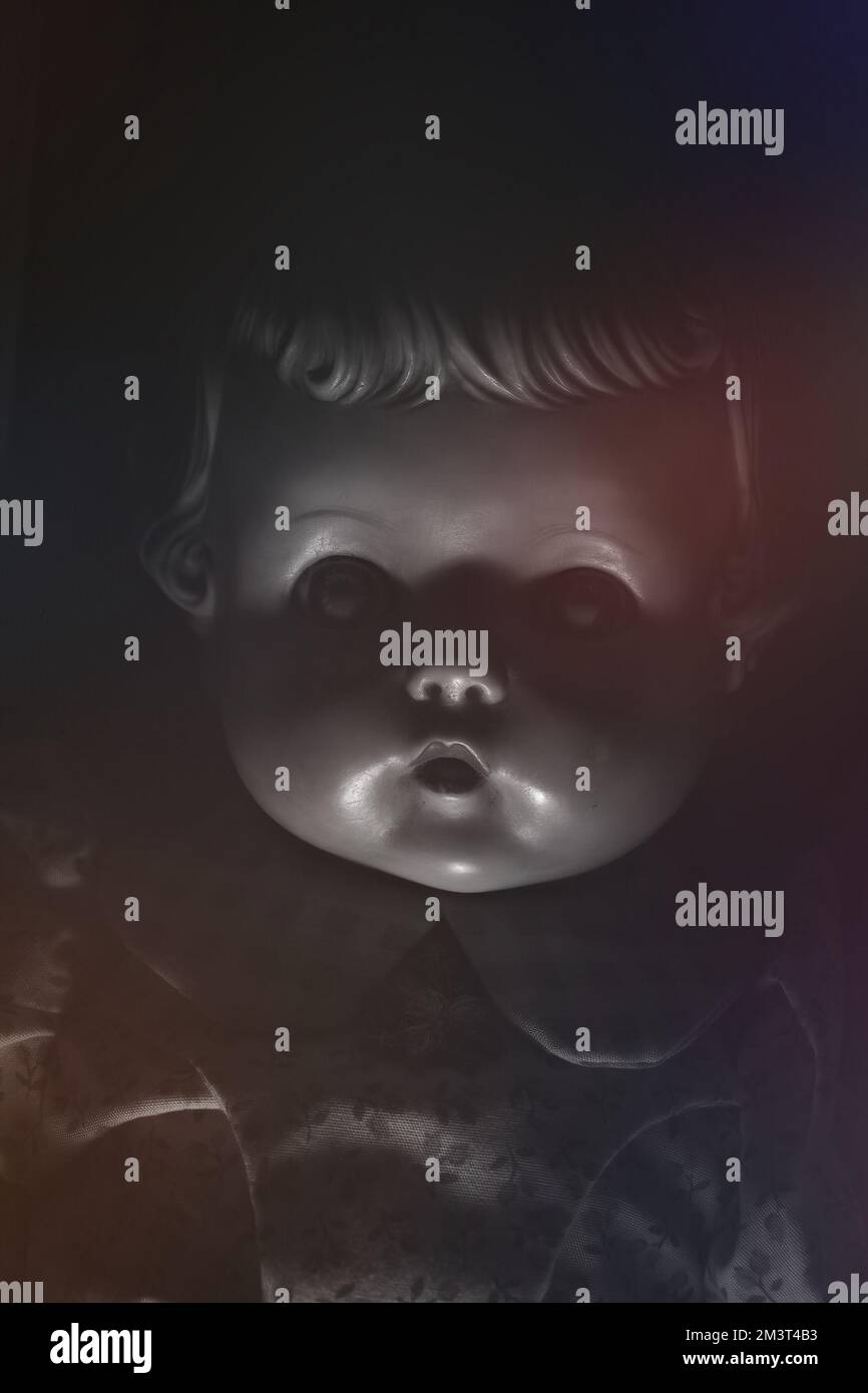 Creepy light and shadows on the face of an antique doll in a dark room ...