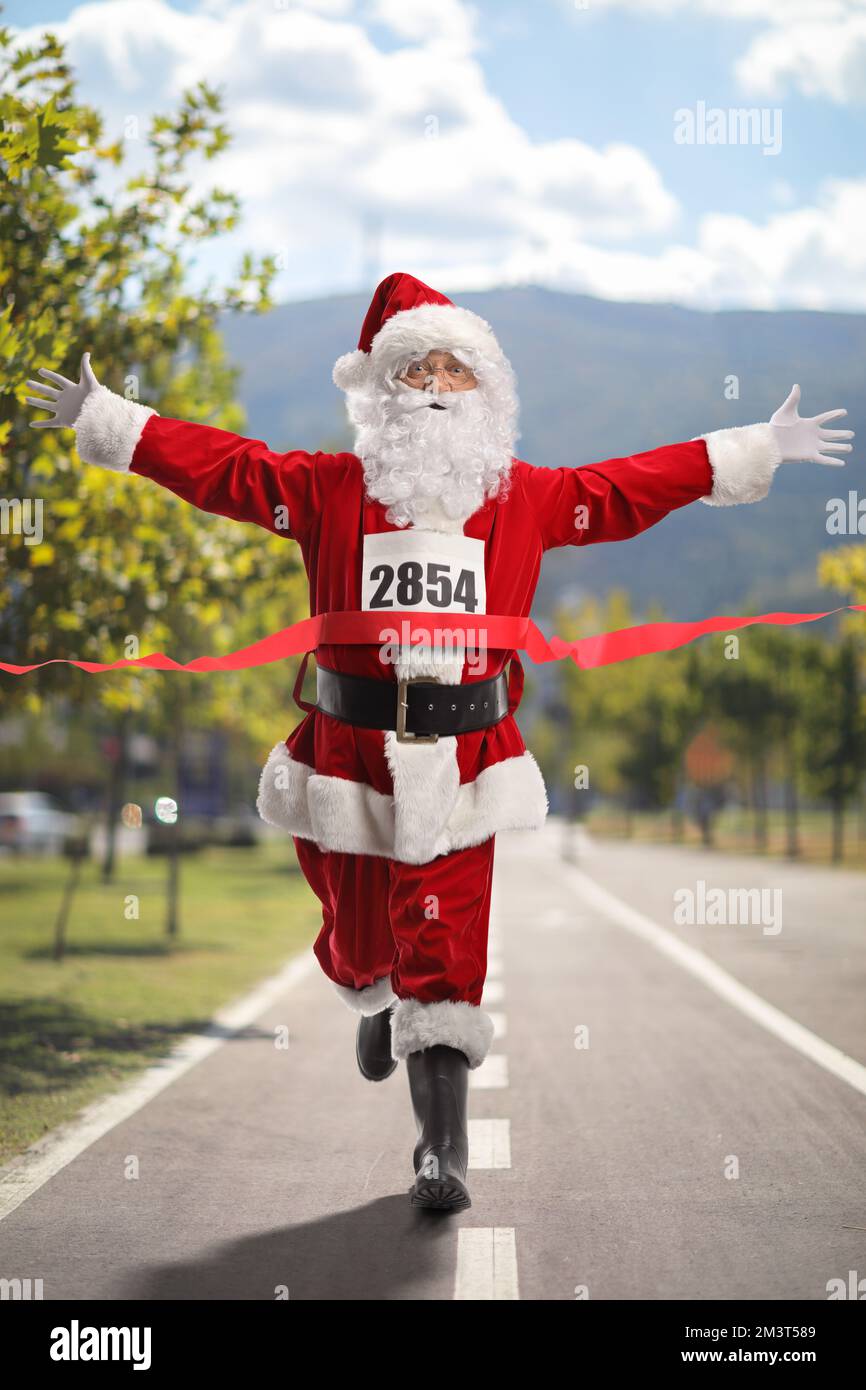 Happy Santa Claus finishing first a race on an asphalt road in the city ...